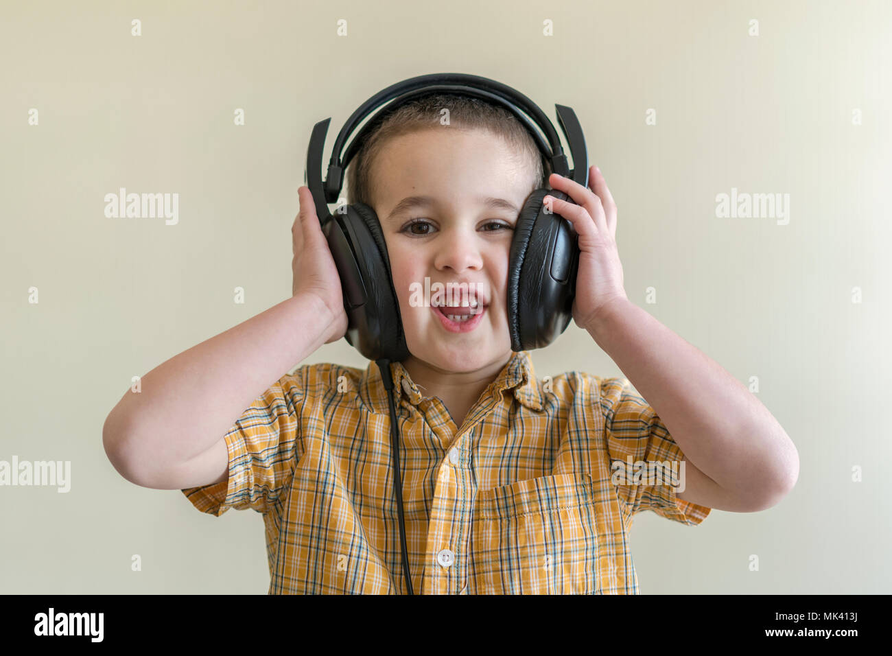 Beautiful baby boy in big headphones. A boy in a plaid shirt listening ...