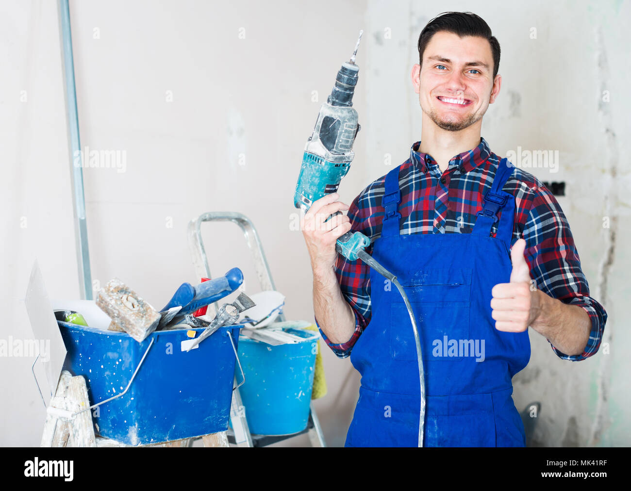 Young builder handyman with hammer in hand giving thumbs up in ...