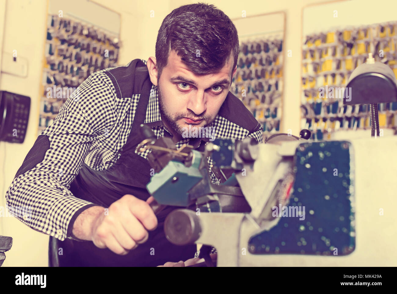Ordinary male worker making key in specialized workshop Stock Photo - Alamy