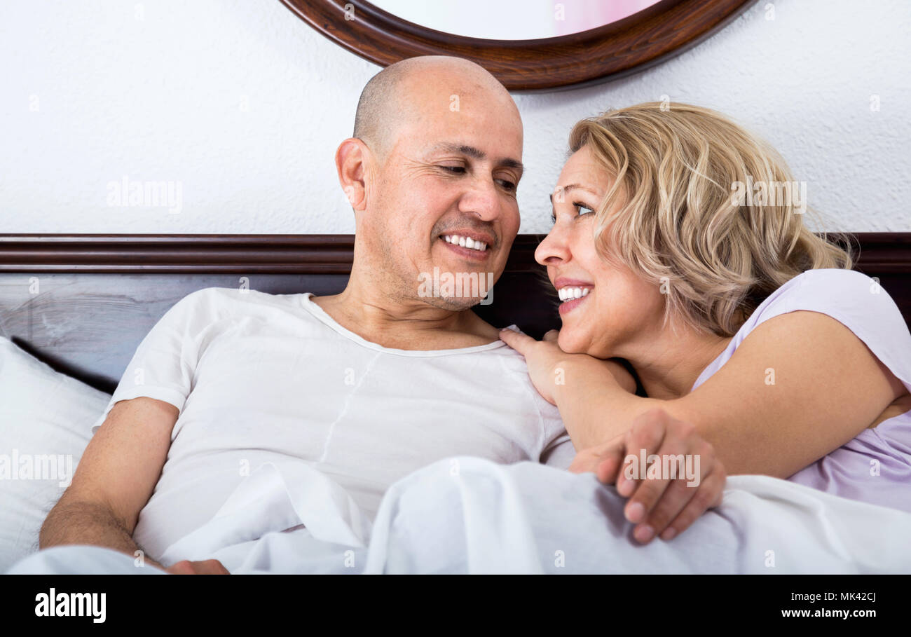 Happy smiling mature loving couple lounging in bed after awaking ...