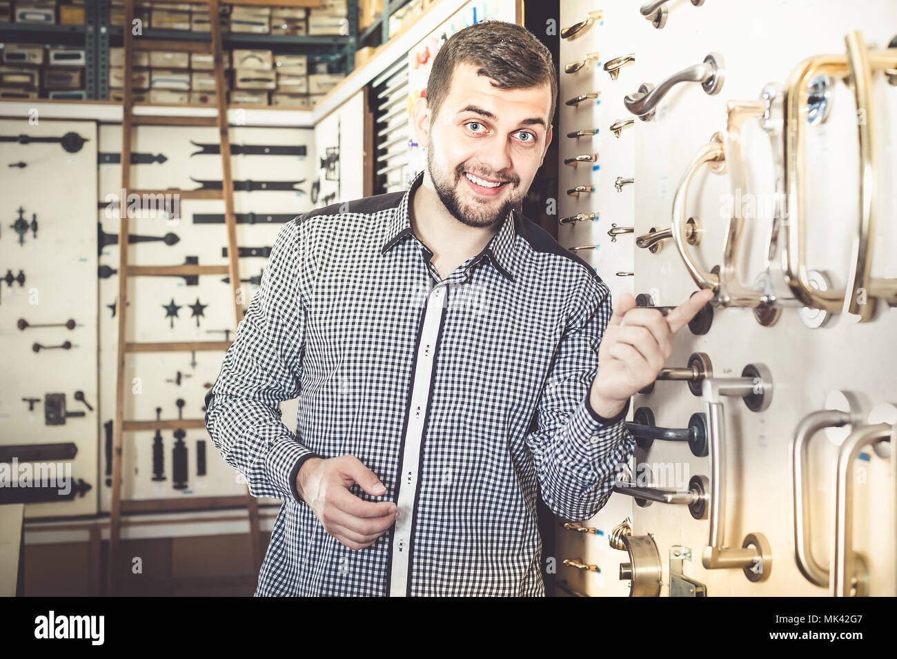 Adult male seller demonstrating door and furniture knobs in houseware ...