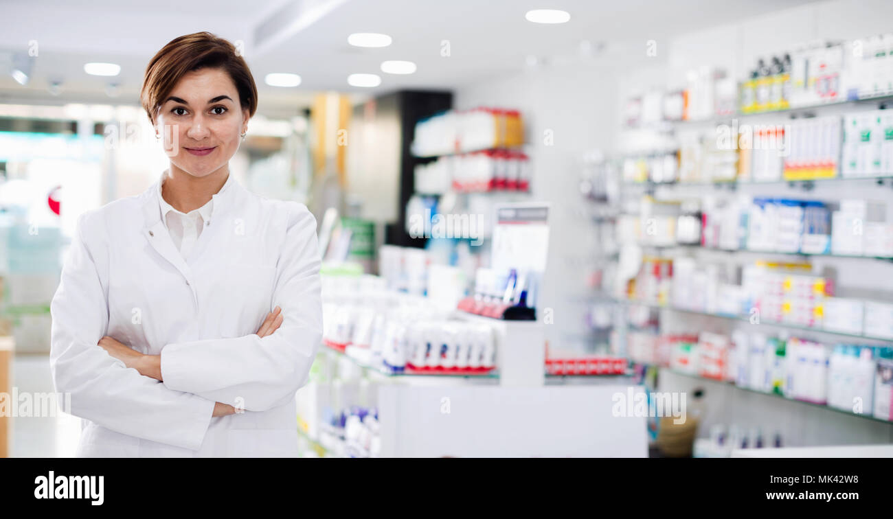 Young diligent friendly female pharmacist arranging displayed ...