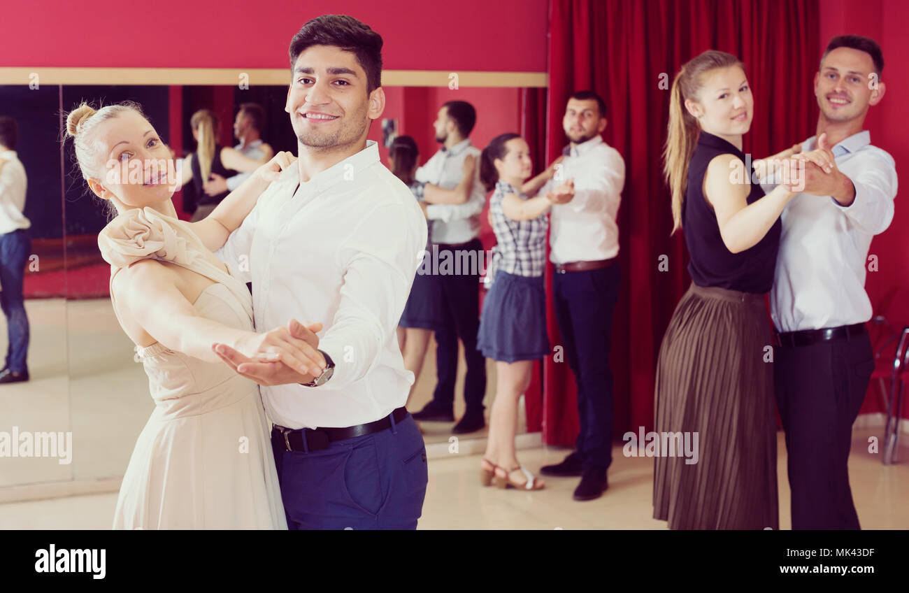 Young positive people dancing together slow ballroom dances in pairs ...