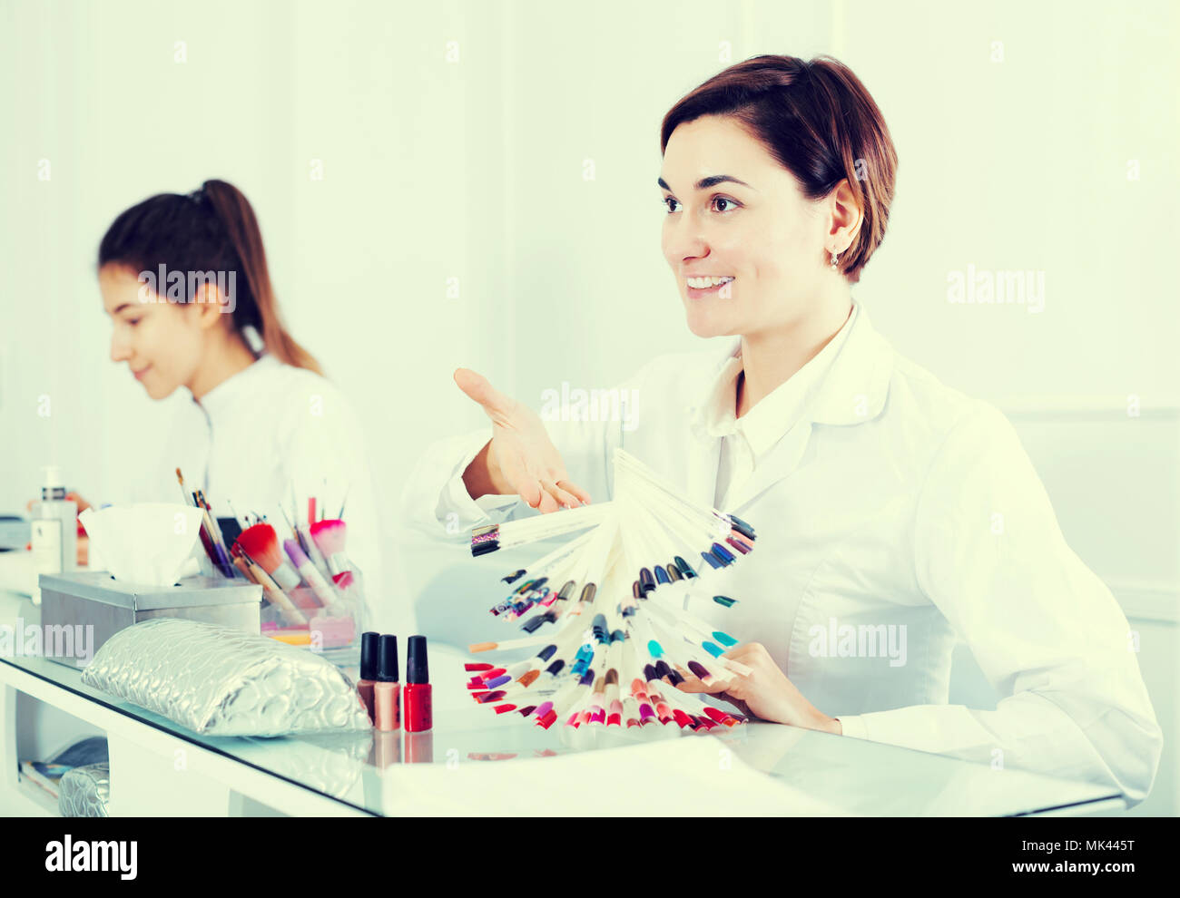 Pretty young woman doing nails displaying polish color schemes in nail ...