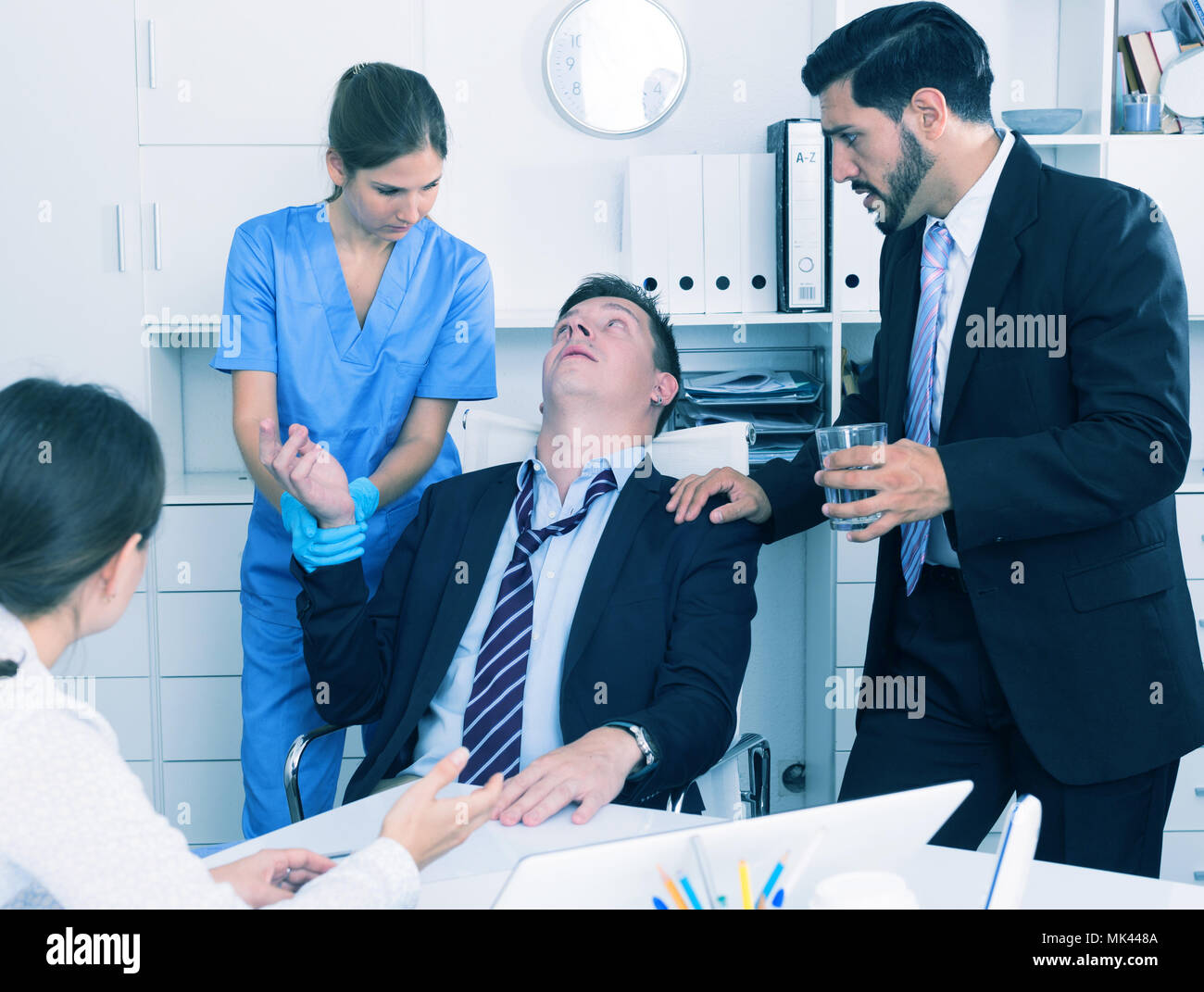 Businessman in fainting receiving first aid at workplace in office ...