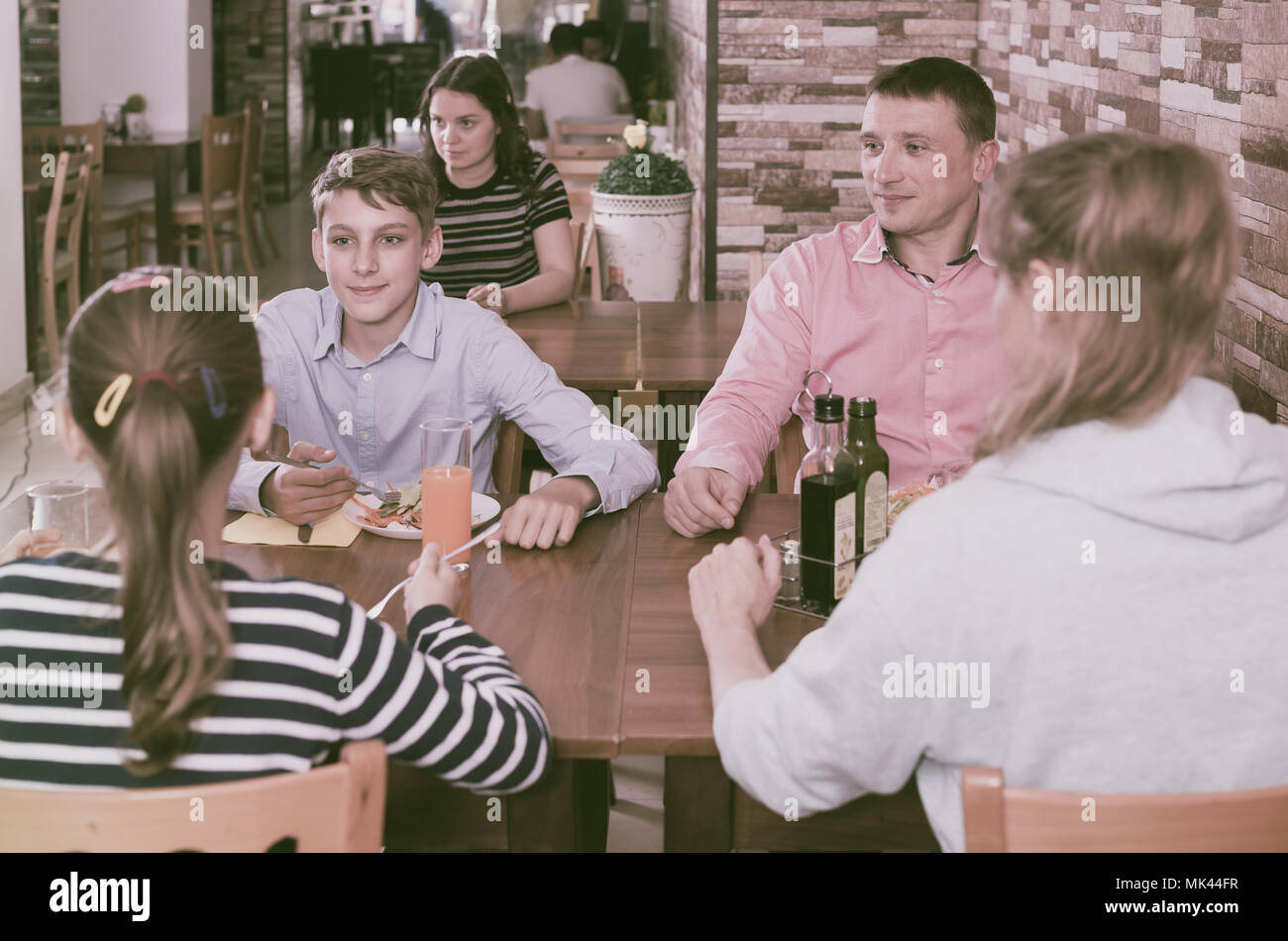 Glad family having conversation at dining table in cafe Stock Photo - Alamy