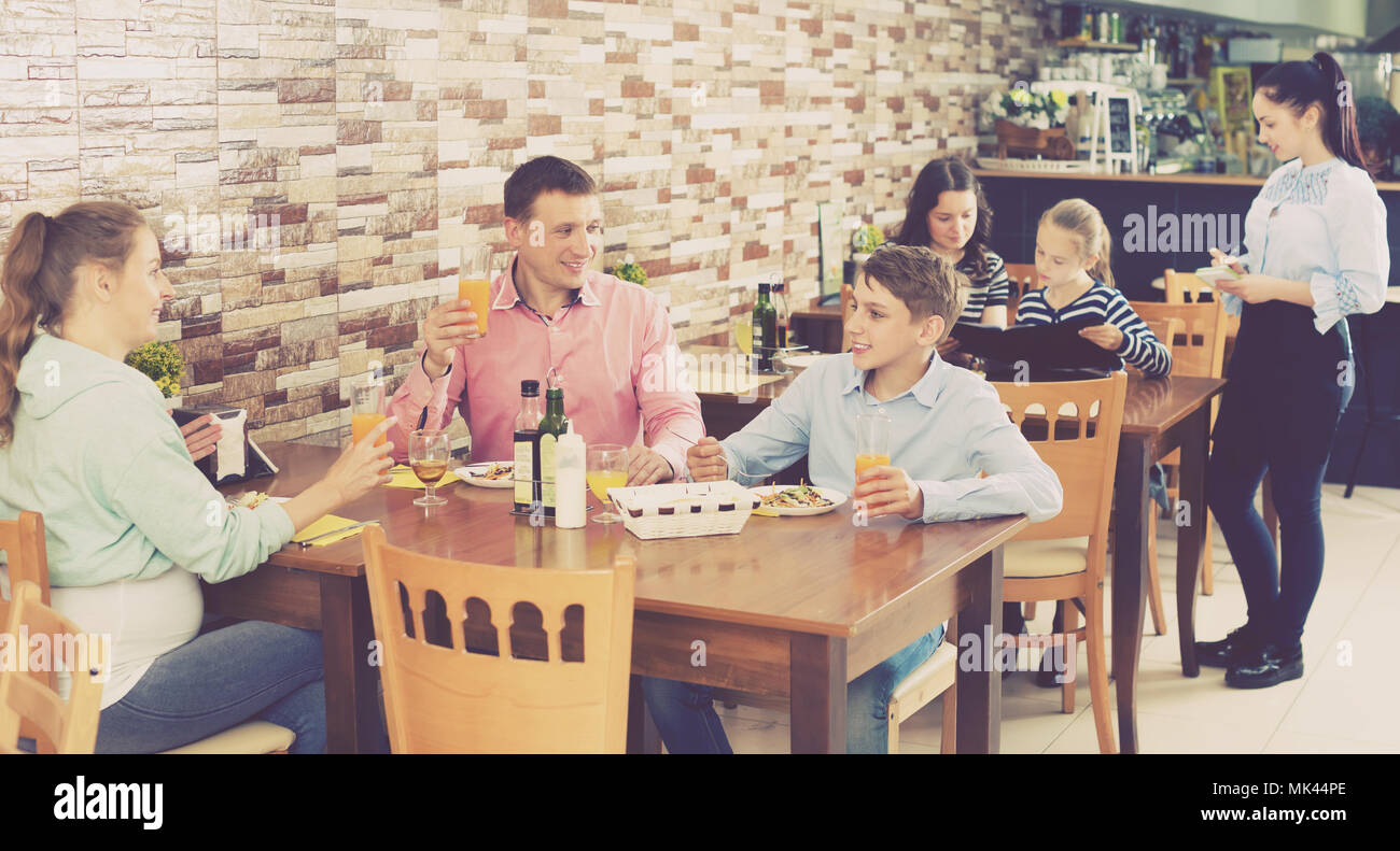 Cheerful family having conversation at dining table in cafe Stock Photo ...