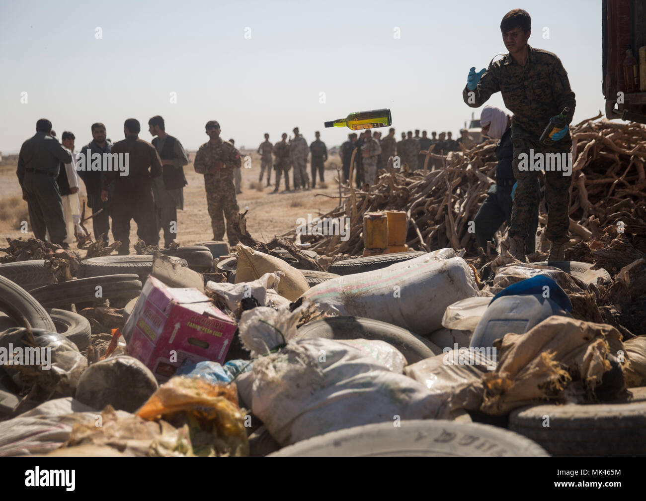 An Afghan National Policemen throws alcohol into the pile of drugs and ...