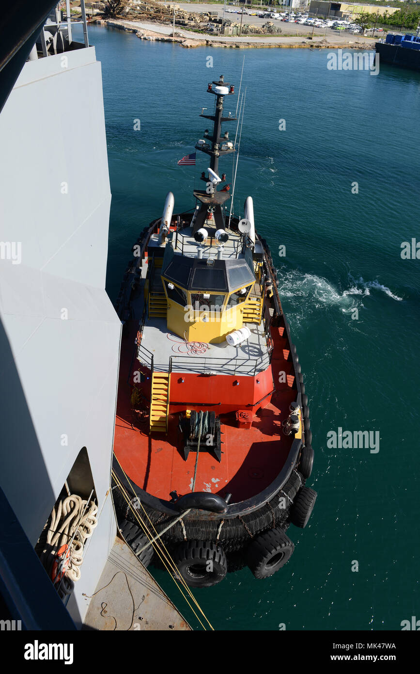 A tug boat eases Military Sealift Command’s USNS Brittin into the Port ...