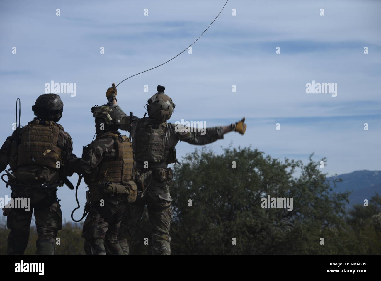 A U.S. Air Force pararescueman and two French Air Commandos signal to ...