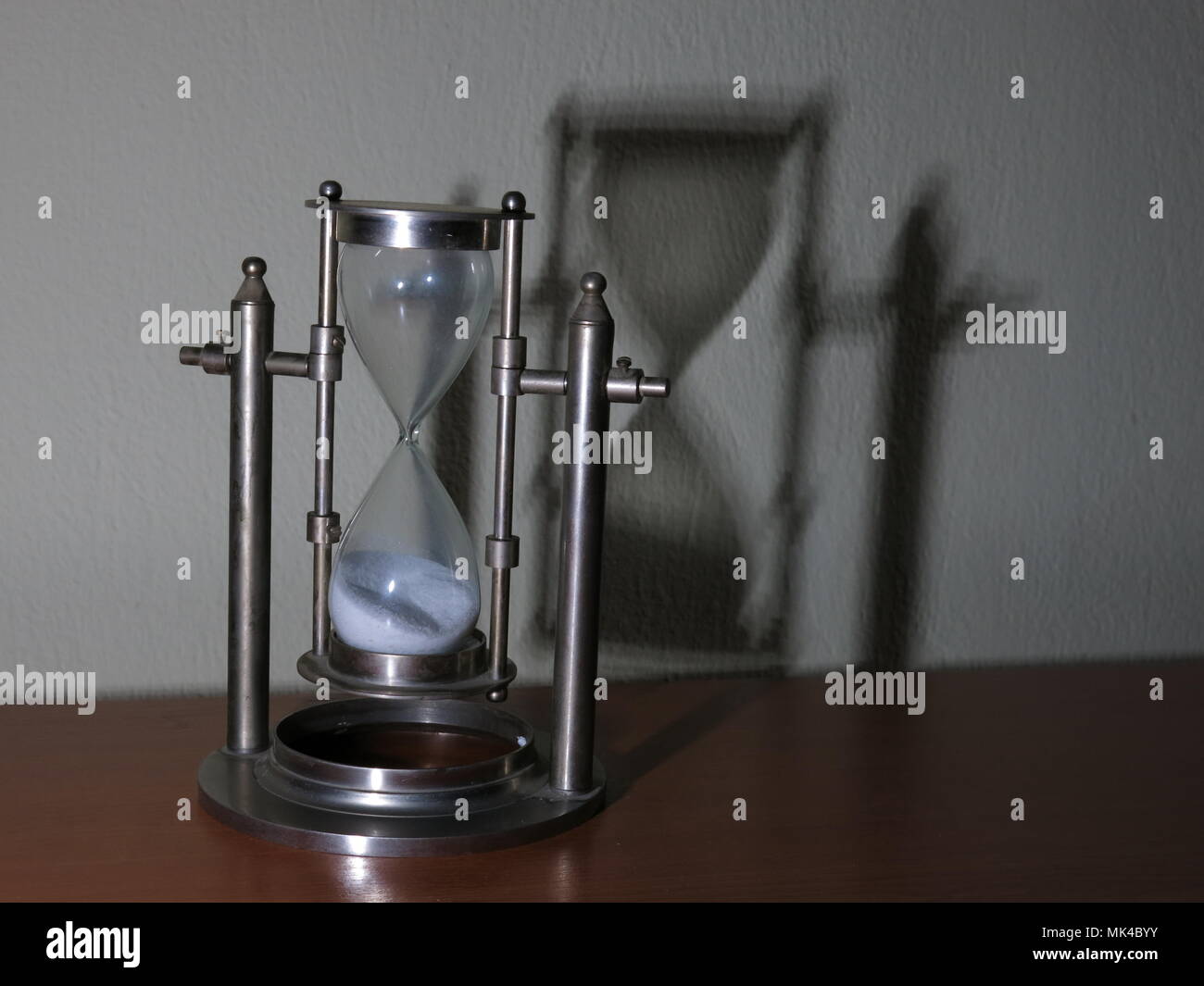 Hourglass casting its shadow against white wall. Concept: passage of ...