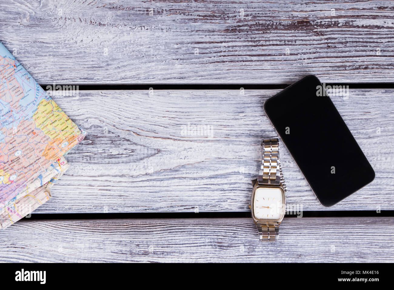 Flat lay of smartphone with luxury watch clock. Wooden desk table with ...