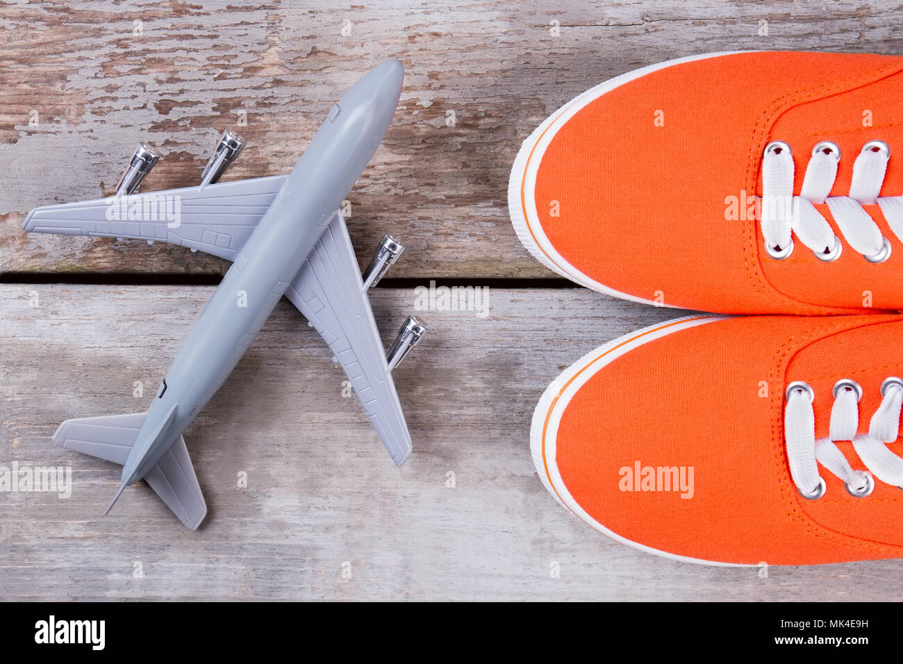Red shoes and toy airplane. Flat lay, top view. Wooden desk surface ...