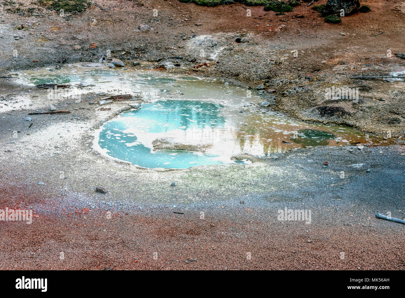 Bright blue hot spring with various colors of soil surrounding the ...
