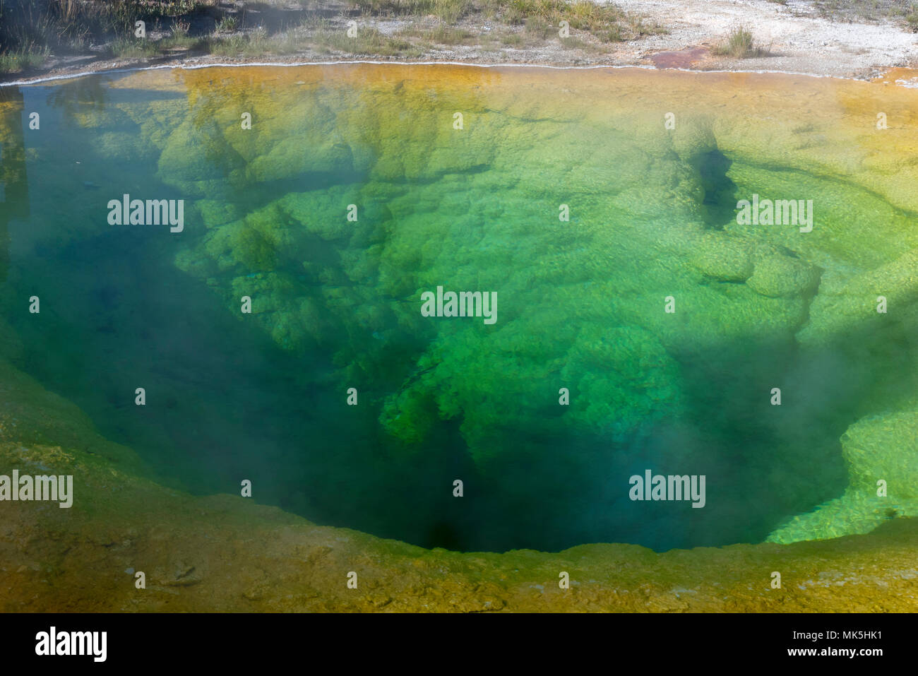 Closeup of geothermal hot spring with blue-green water and rusty edges ...