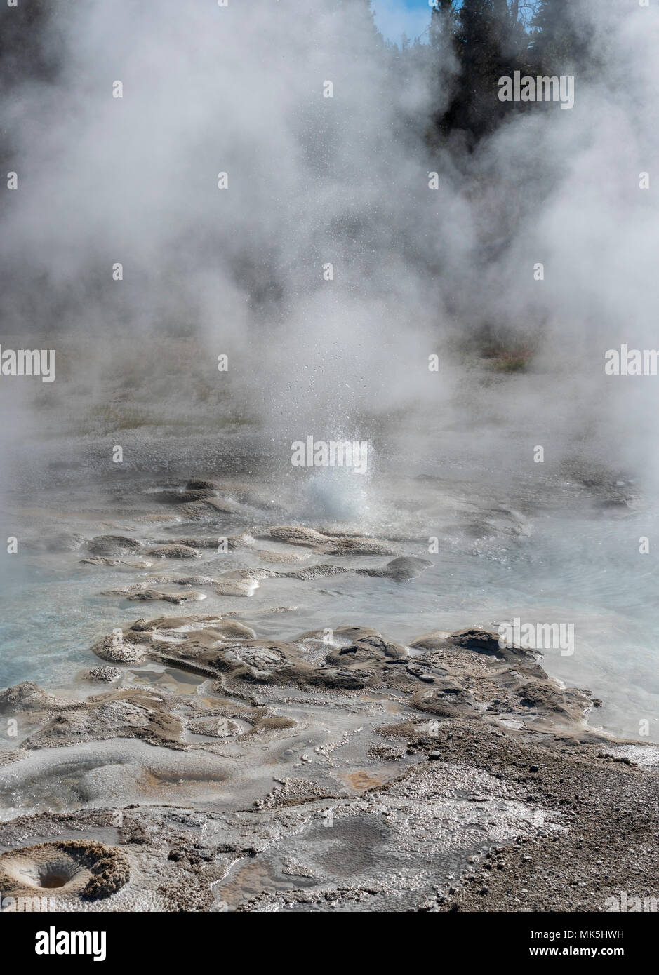 Blue water bubbling hot spring with steam clouds rising up into air ...