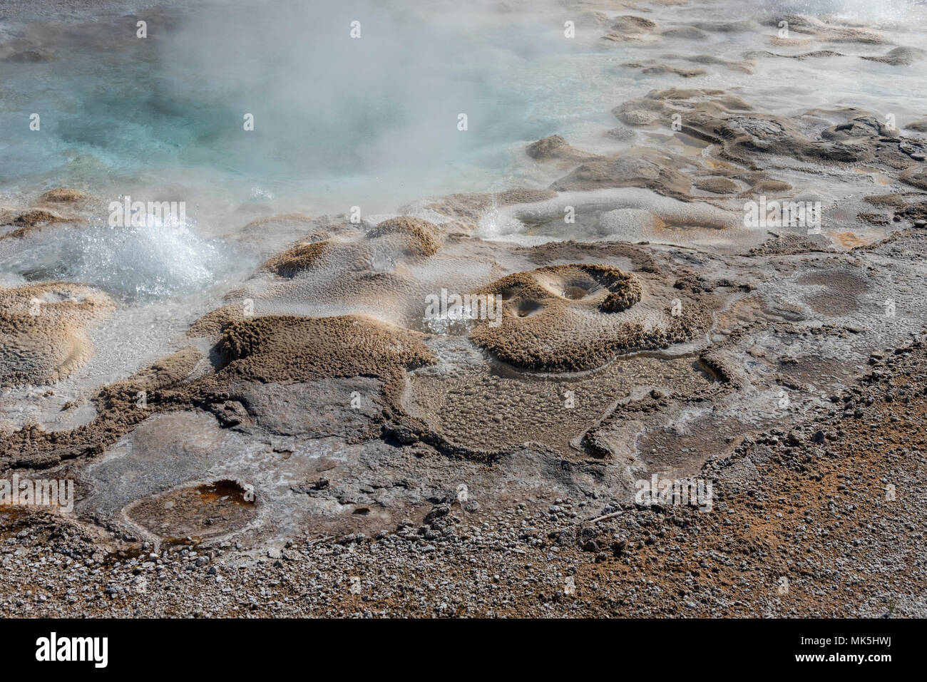 Bright blue hot spring with steam rising up surrounded by mineral ...