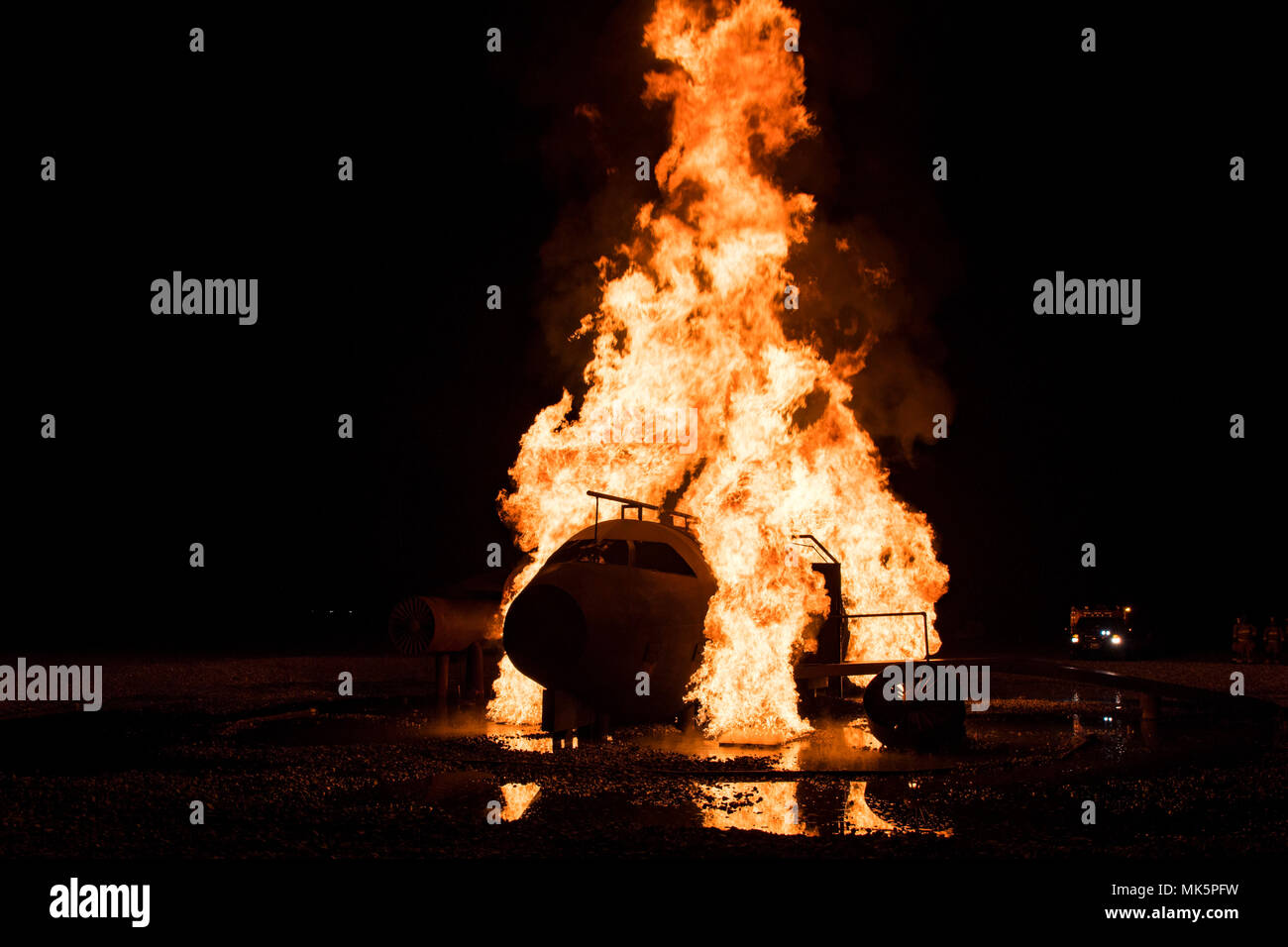 Flames rise from a prop aircraft during nighttime live-fire training ...