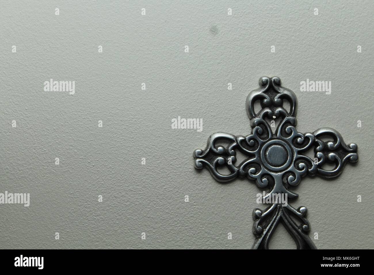 a metal cross against a grey background in a portion of the lower right ...