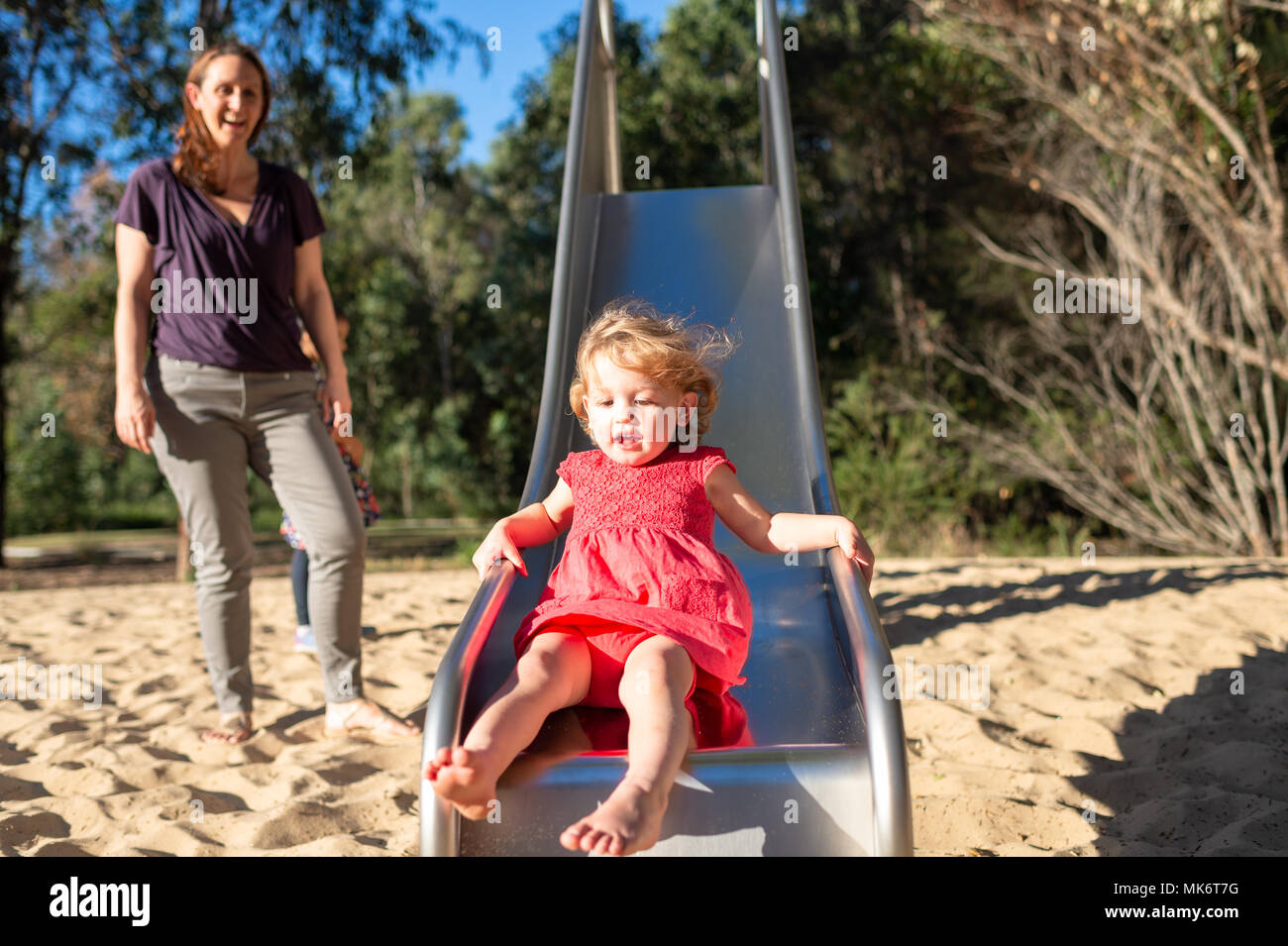 Mother and daughter having fun on a slippery slide in a park Stock ...