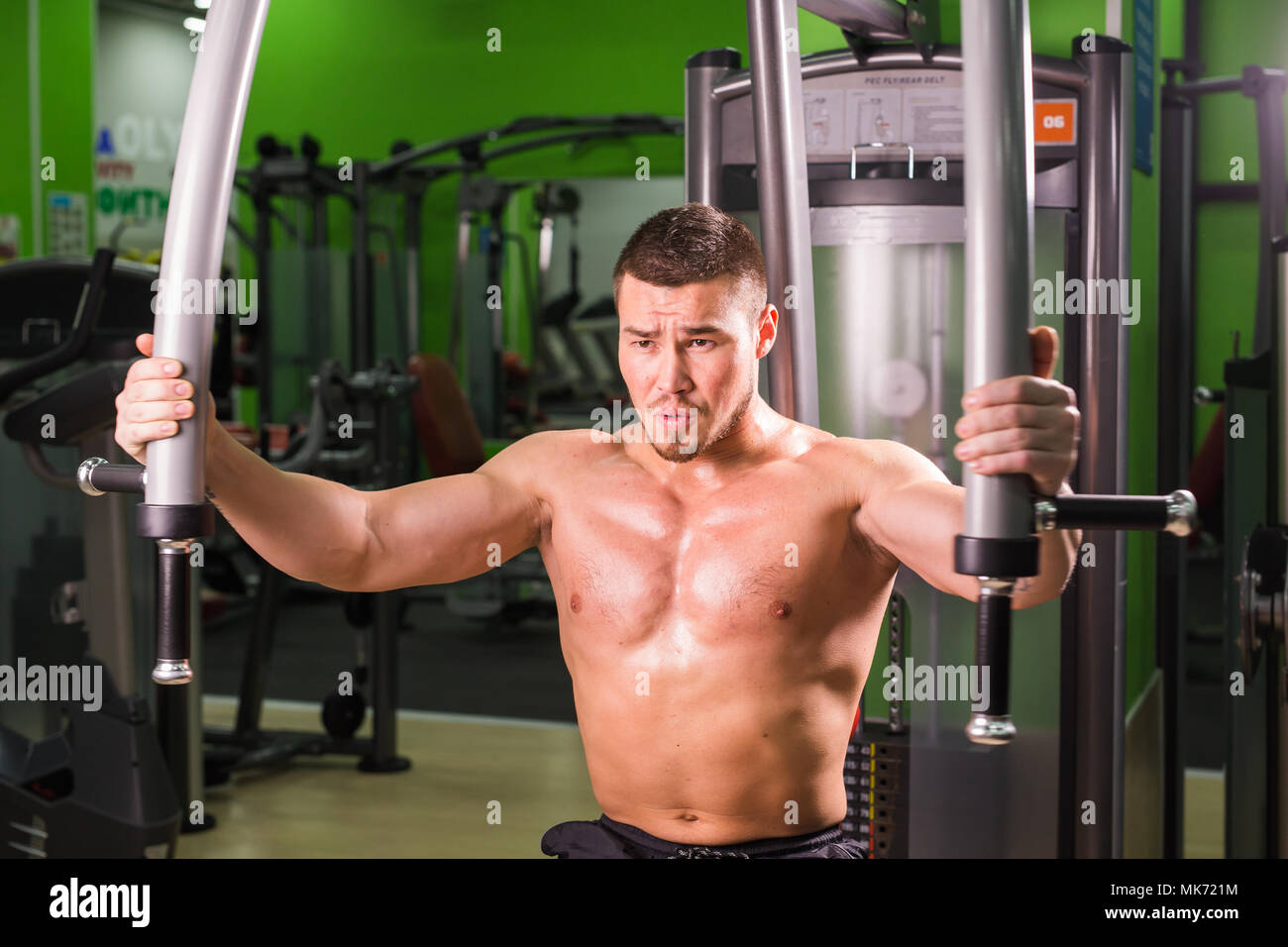 Man doing fitness training on a butterfly machine with weights in a gym ...