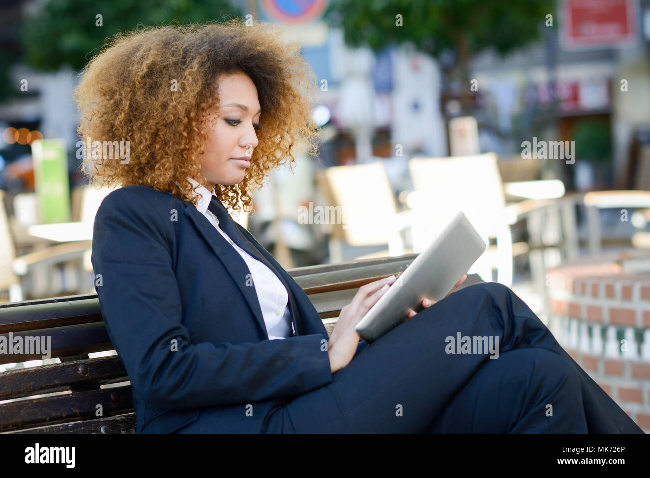 Beautiful black woman using tablet computer in urban background ...