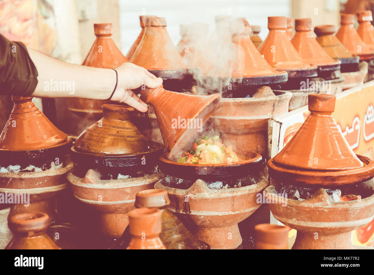 Cooking traditional Moroccan dish, meat and vegetable in ceramic tajine ...