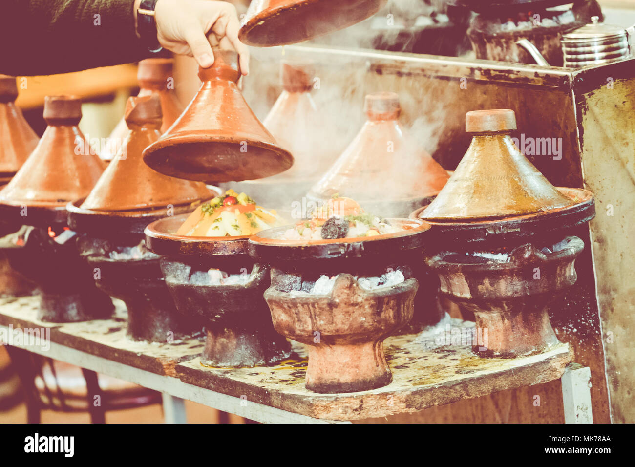 Cooking traditional Moroccan dish, meat and vegetable in ceramic tajine ...