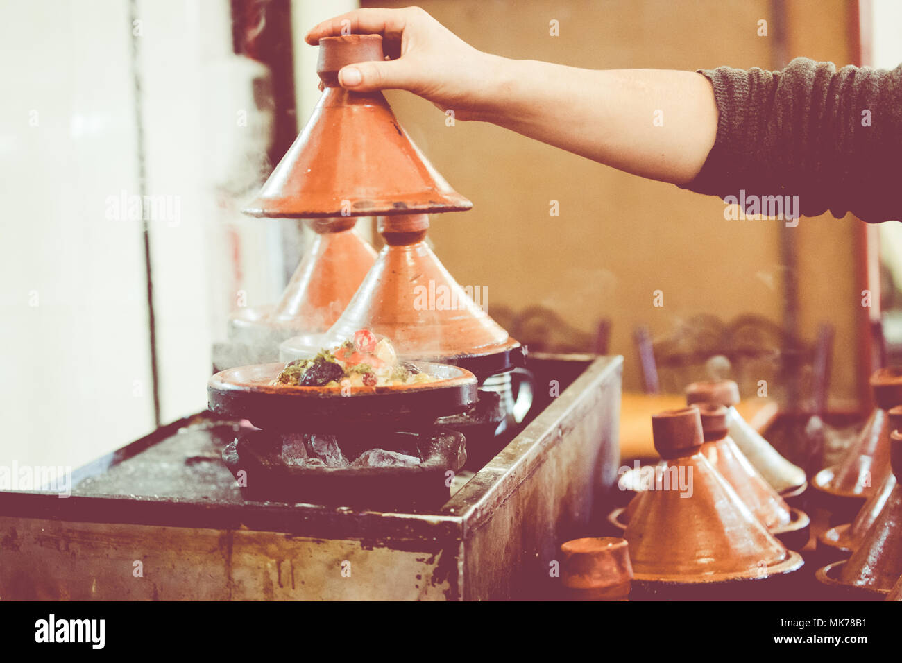 Cooking traditional Moroccan dish, meat and vegetable in ceramic tajine ...