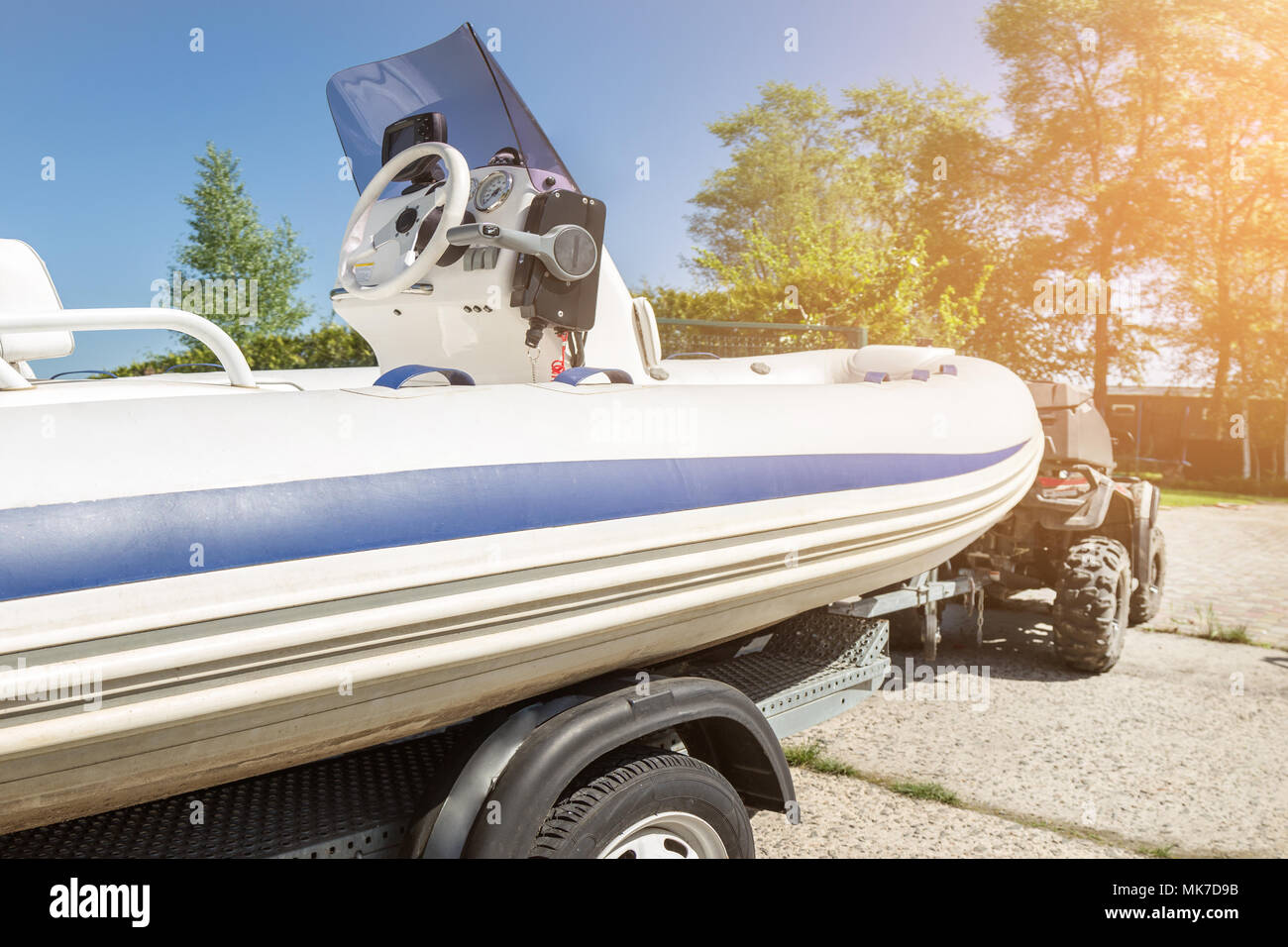 Transportation of inflatable boat on trailer. ATV quadbike moves ship ...