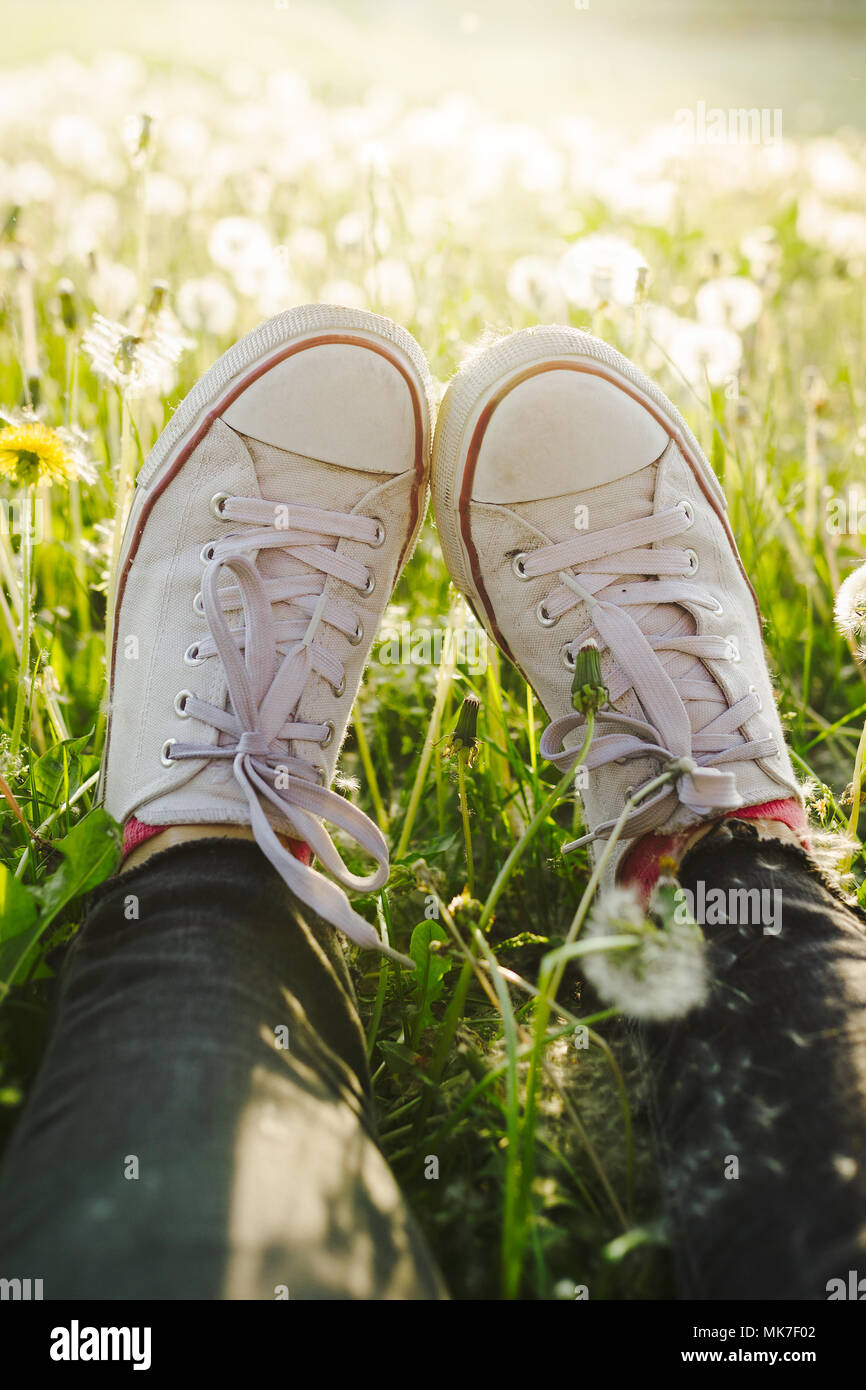 Female legs in white canvas sneakers and black jeans laying in the ...