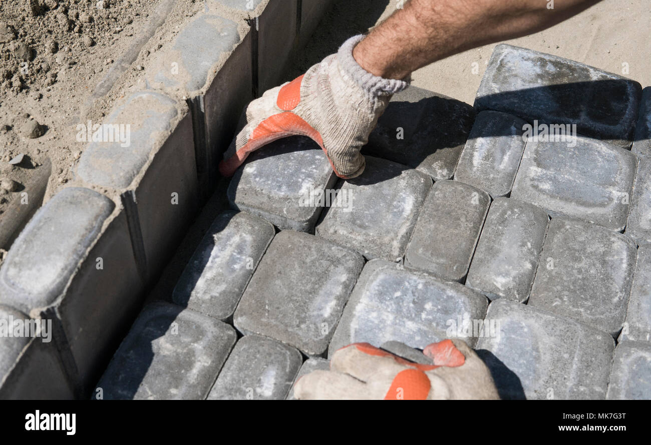 Hands of a builder in his orange gloved hands fitting laying new ...