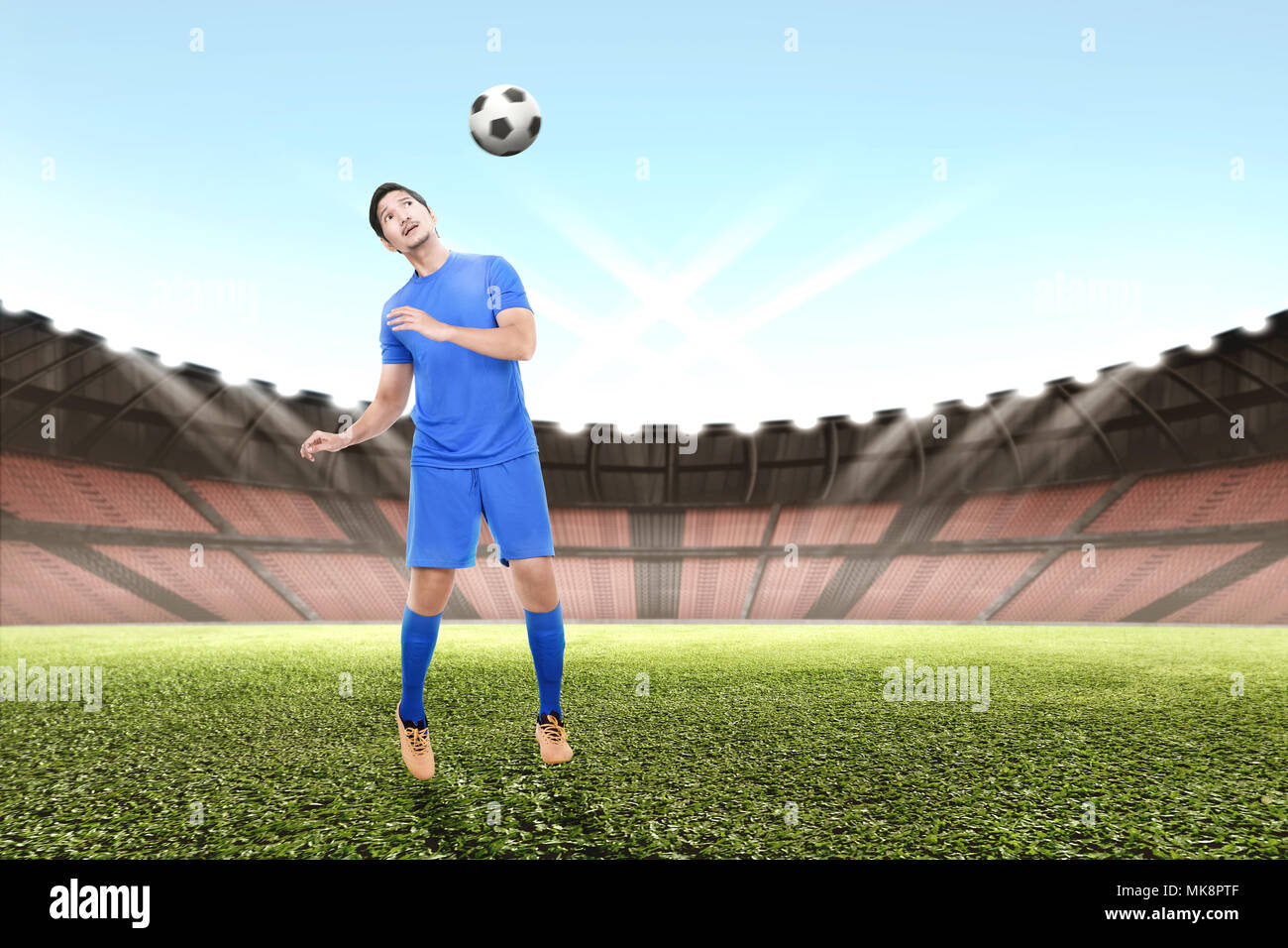 Young asian soccer player man jump and heading the ball on the field ...