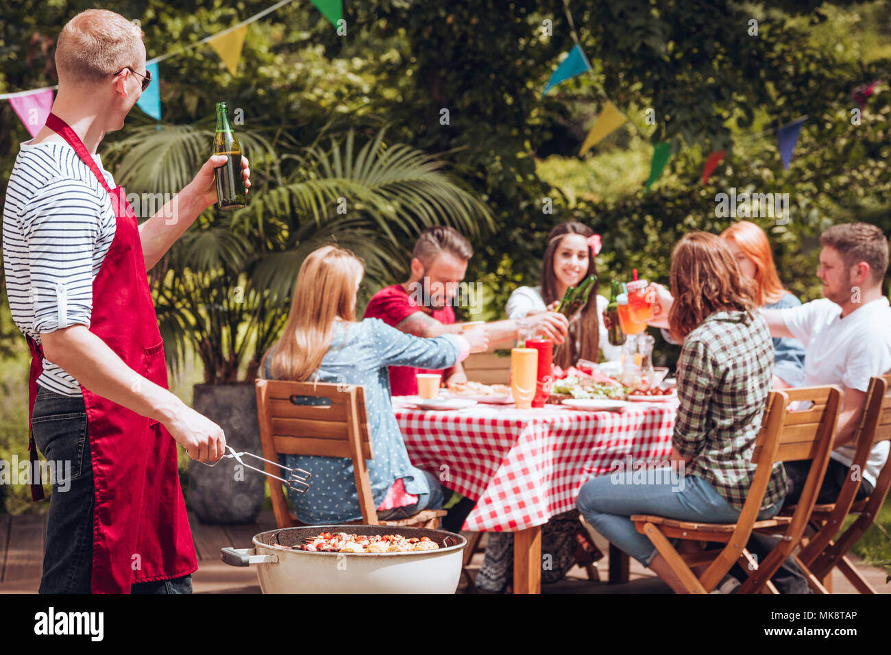 Happy cook drinking beer and grilling food during meeting with friends ...