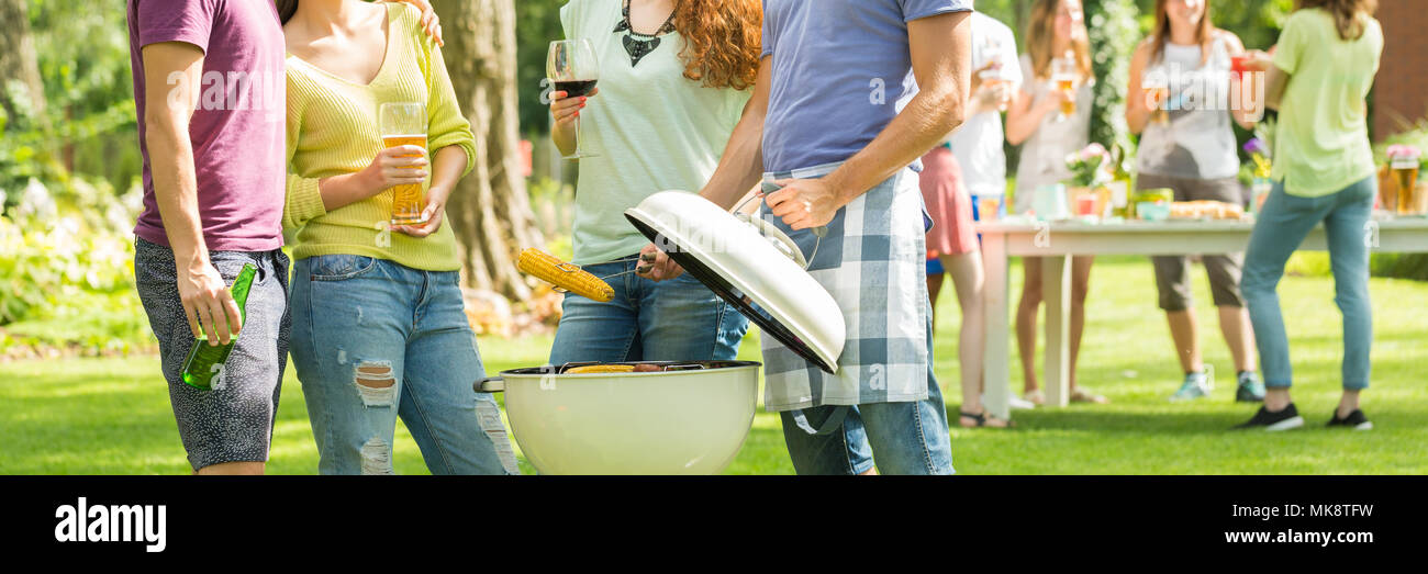 Group of friends standing aroung a barbeque in a garden Stock Photo - Alamy