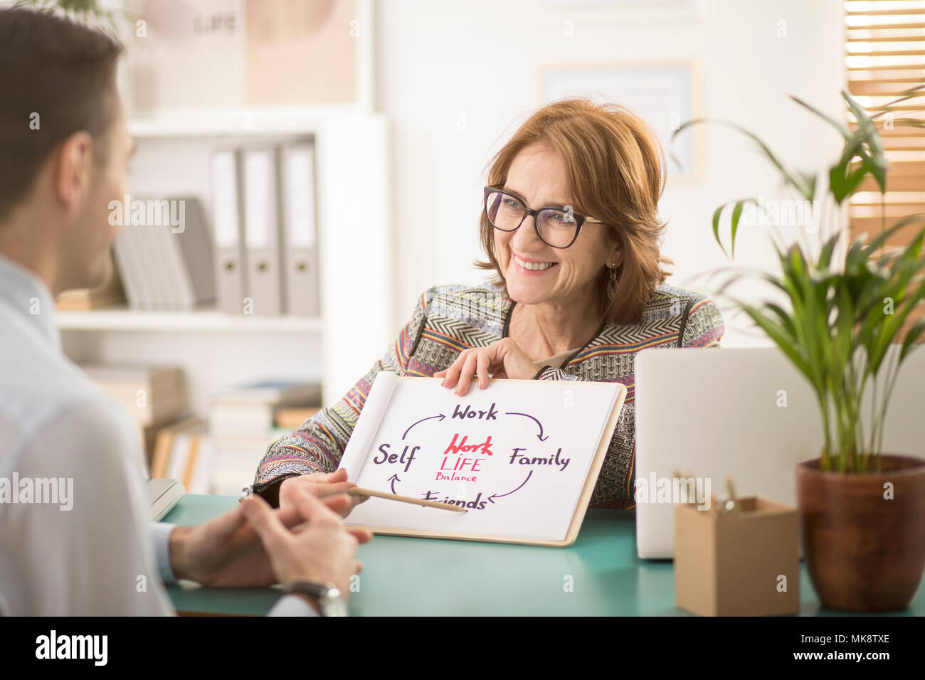Smiling coach talking about work-life balance with a corporate employee ...