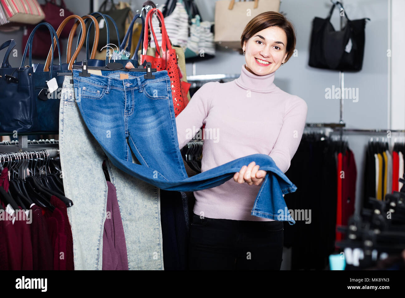 Woman demonstrates bought jeans in a clothing store Stock Photo - Alamy