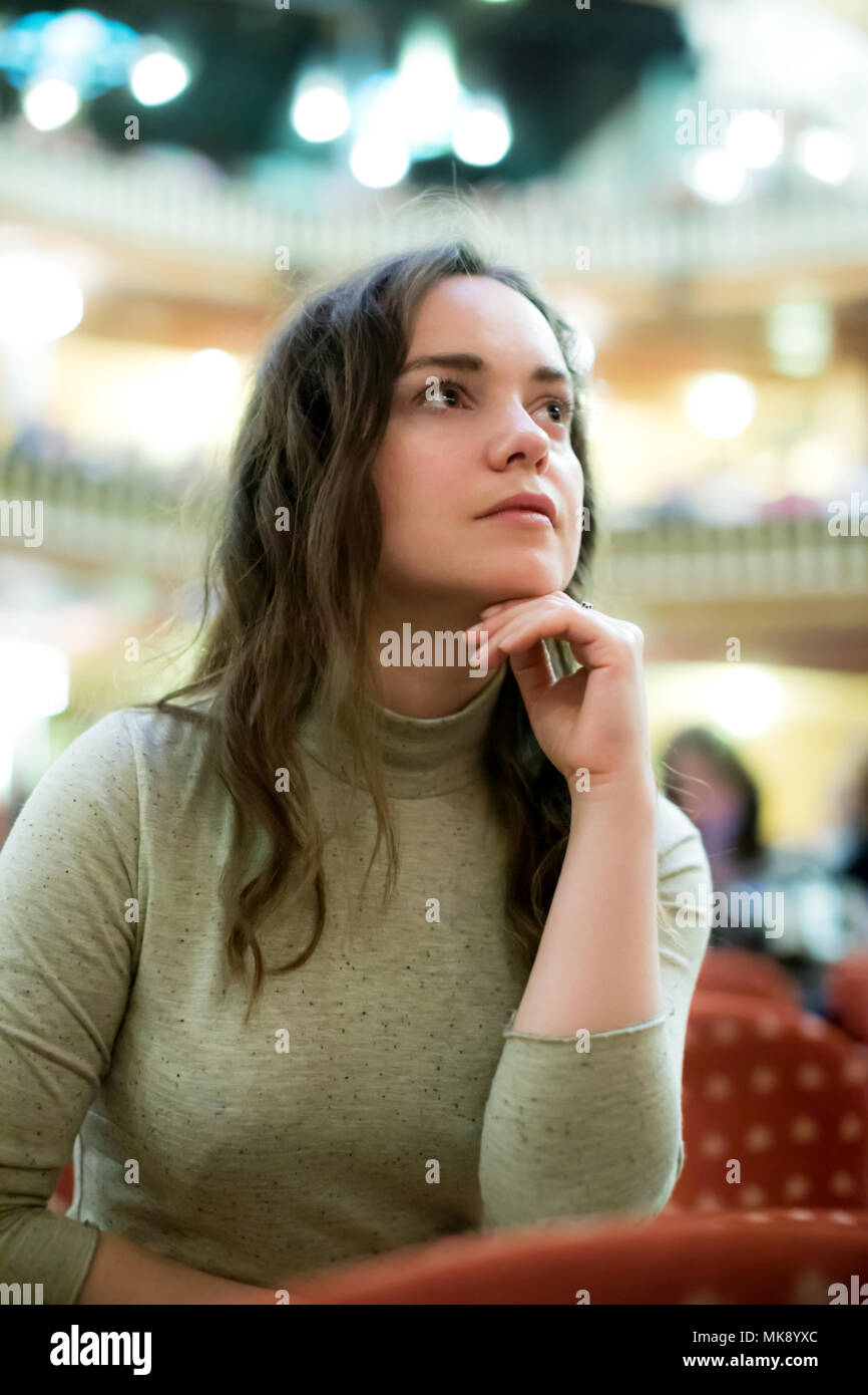 Portrait of pretty girl sitting in theatre salon and watching show ...