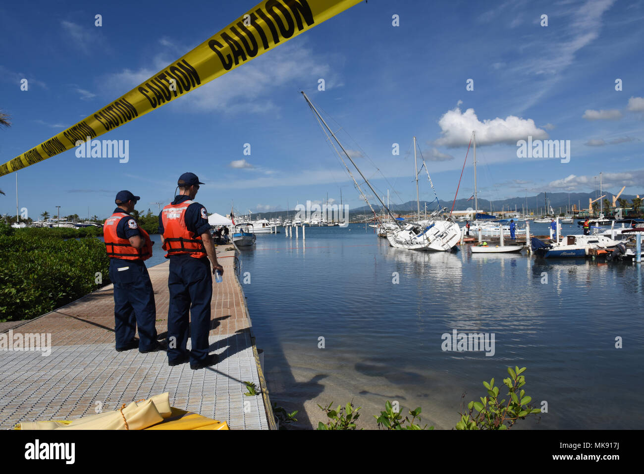 Two Coast Guardsmen observe a grounded vessel in preparation for ...