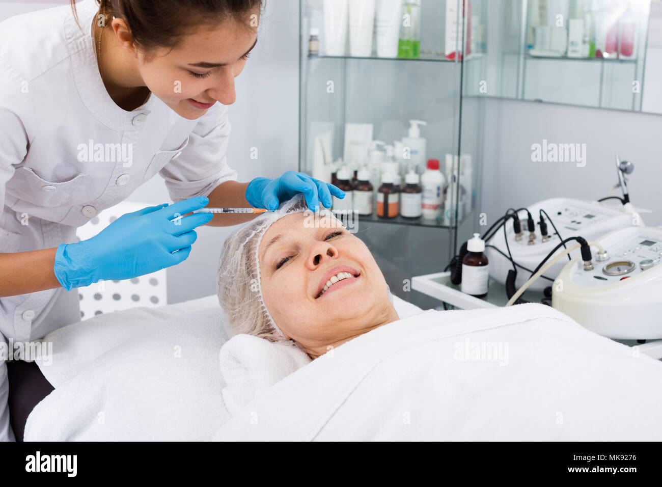 Woman doctor making beauty injection to aged female client Stock Photo ...