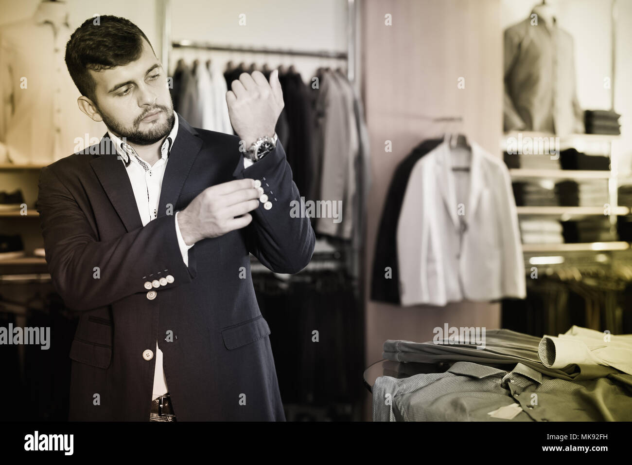 Glad male customer choosing jacket in men clothes shop Stock Photo - Alamy