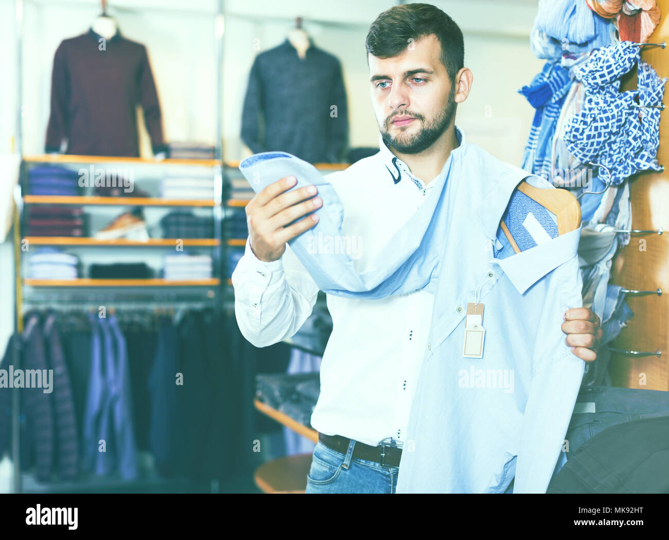 Male customer looking for classic shirt in clothes store Stock Photo ...