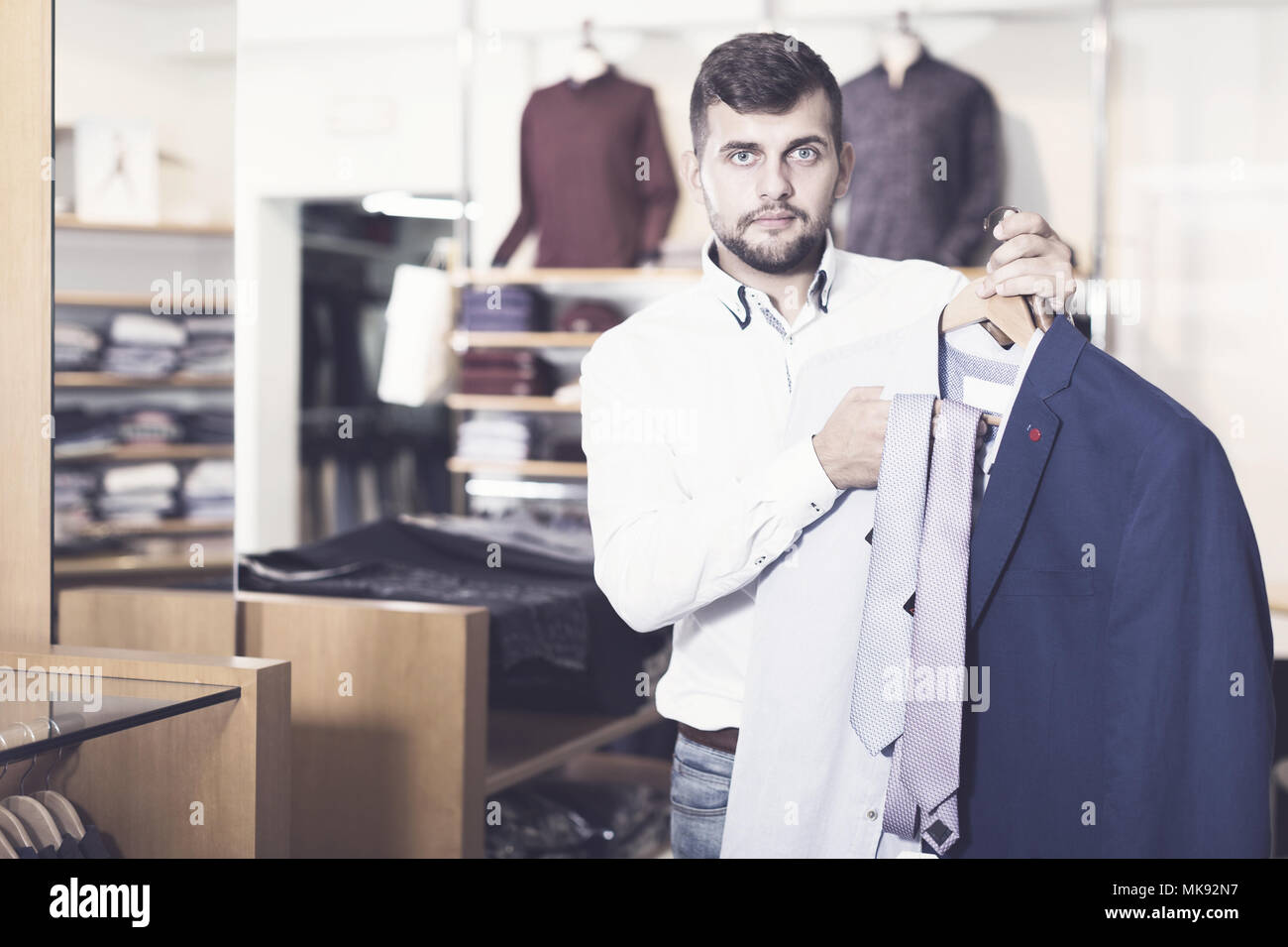 smiling owner guy displaying jacket in fashion store Stock Photo - Alamy