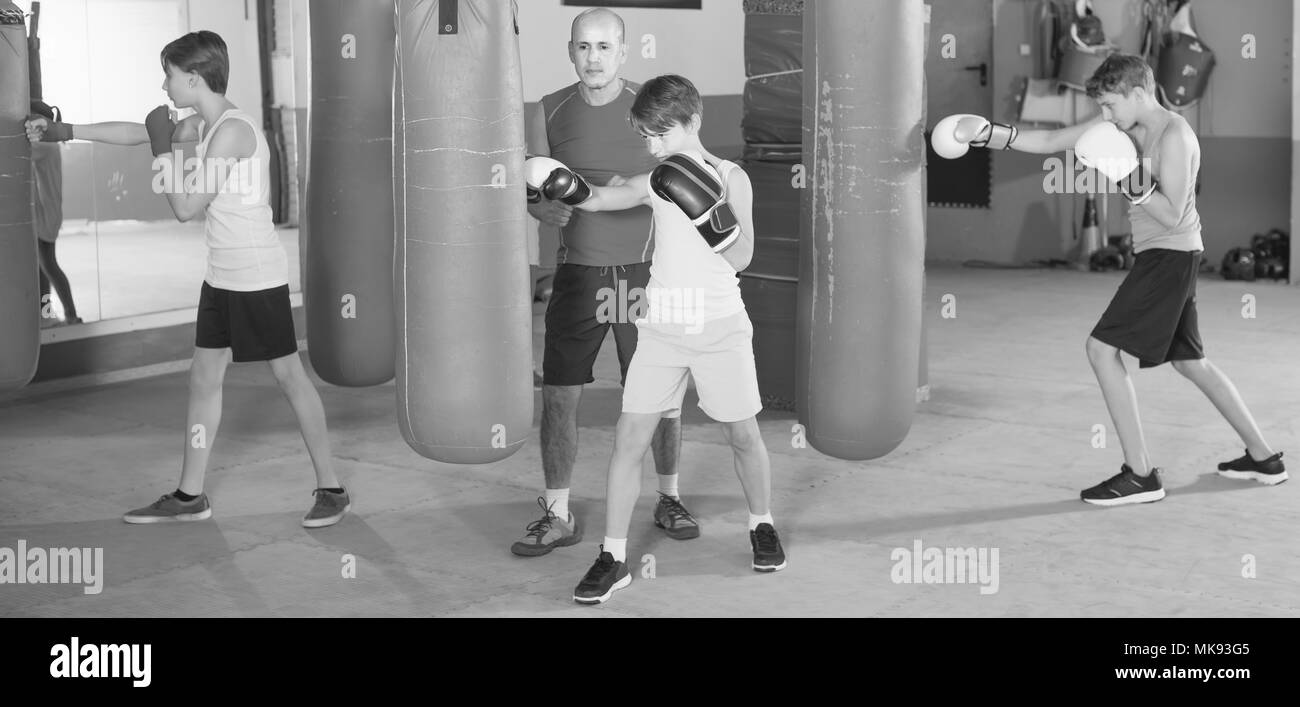 Boy at boxing workout on punching bag with instructor Stock Photo - Alamy