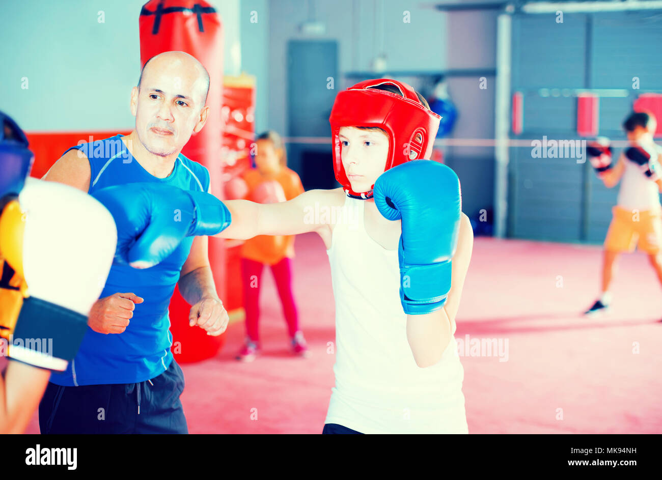 Boxing instructor controls the sparring between the two boys in the gym ...