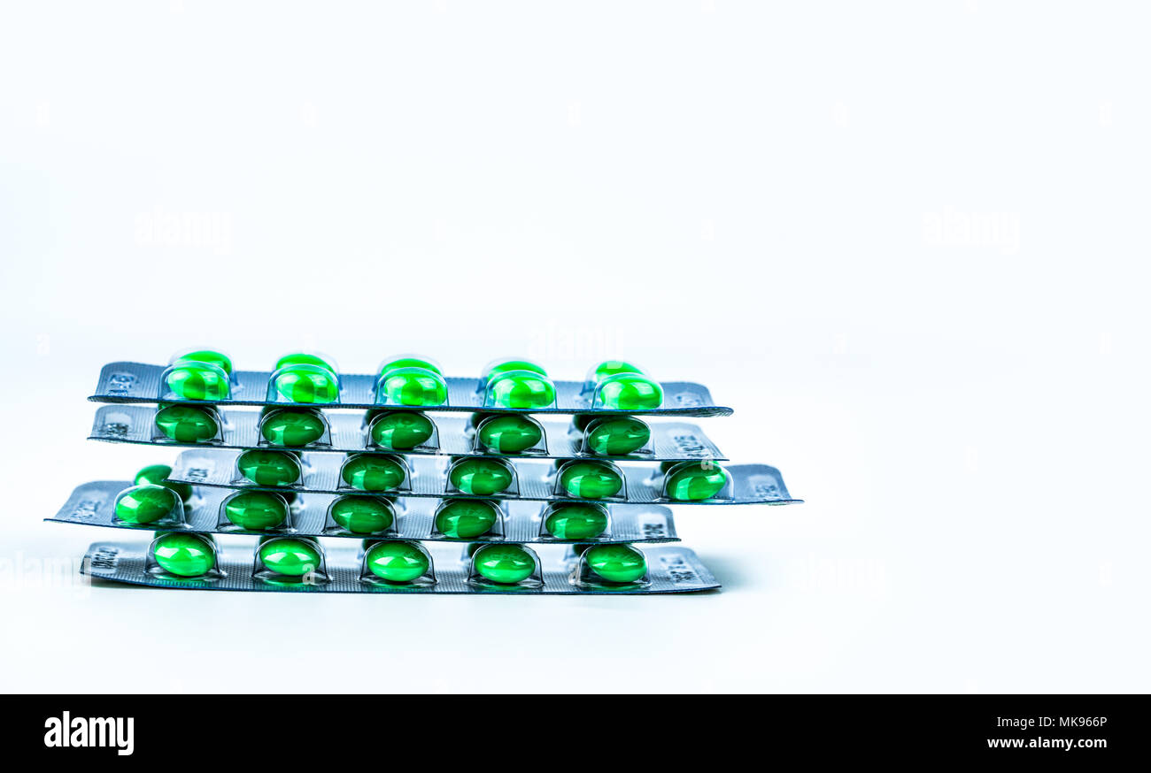 Stacks of green round sugar-coated tablet pills in blister packs on ...