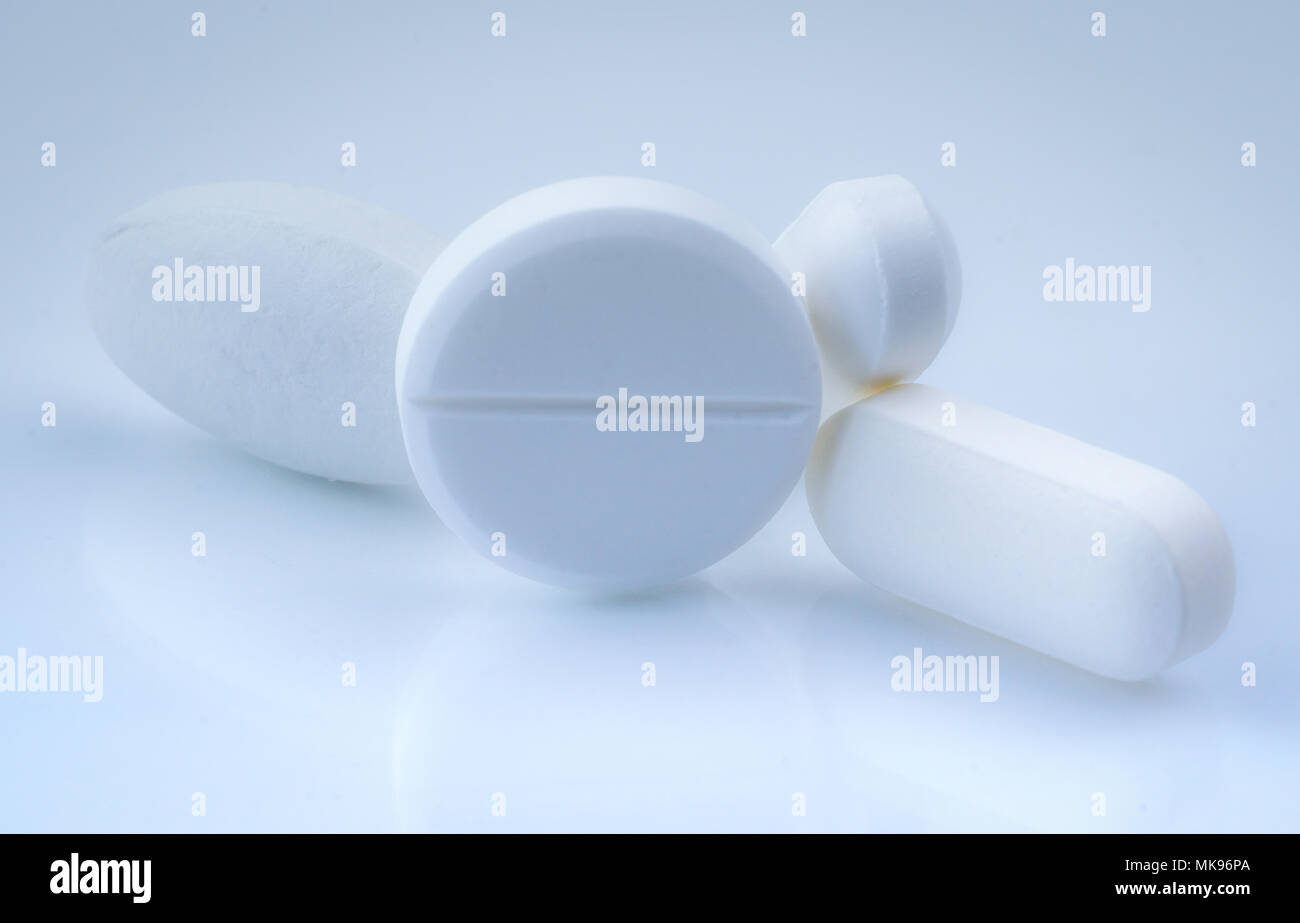 Pile of white round and oblong shape tablet pills isolated on white ...