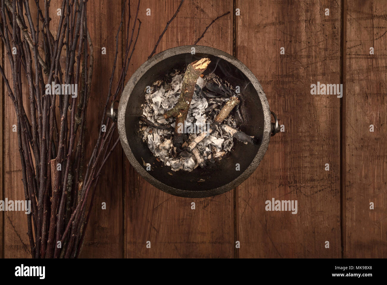 An overhead photo of a witch's cauldron with ashes and wooden sticks ...