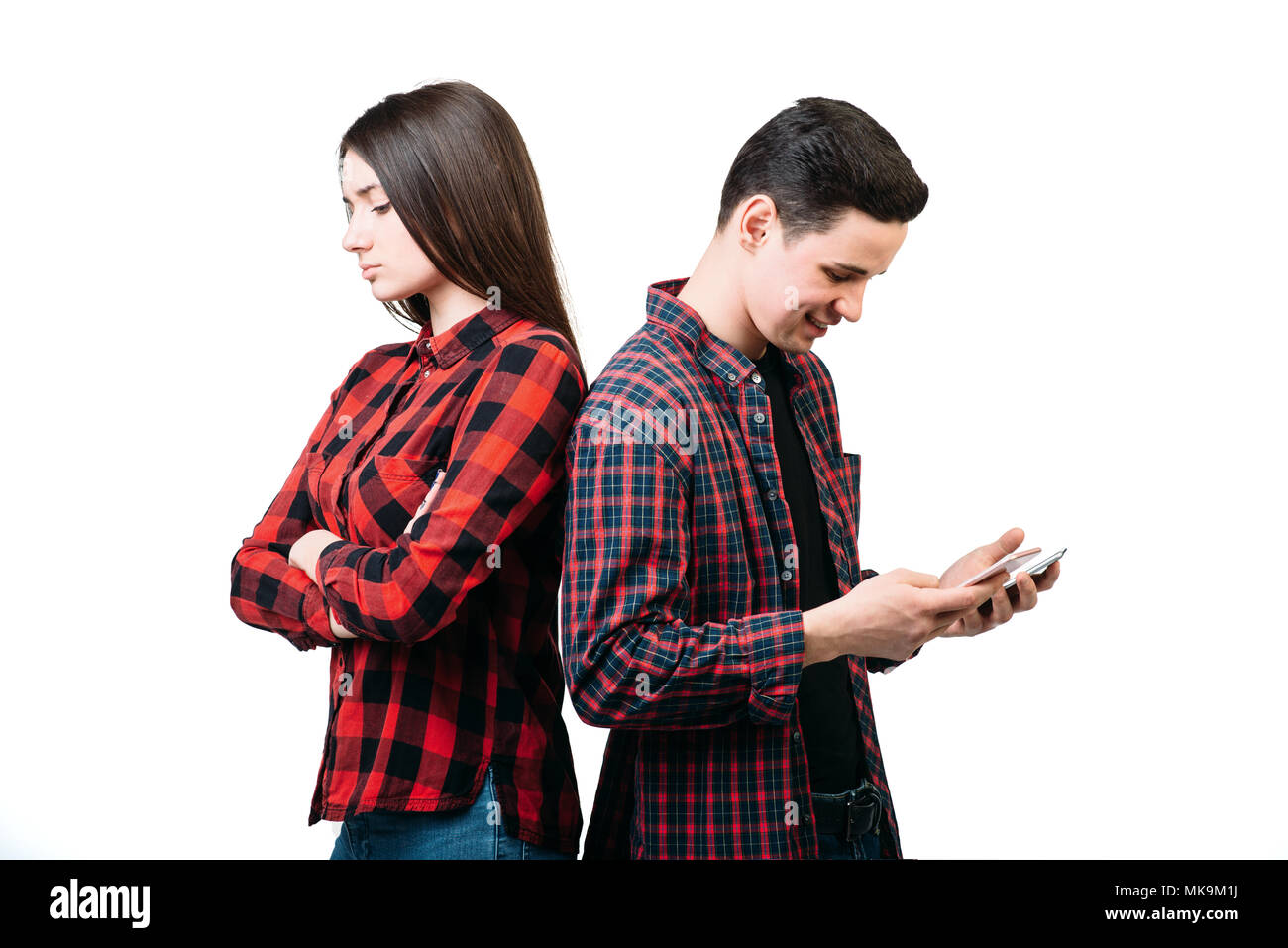 Smartphone addicted people. Couple standing back to back, man using ...