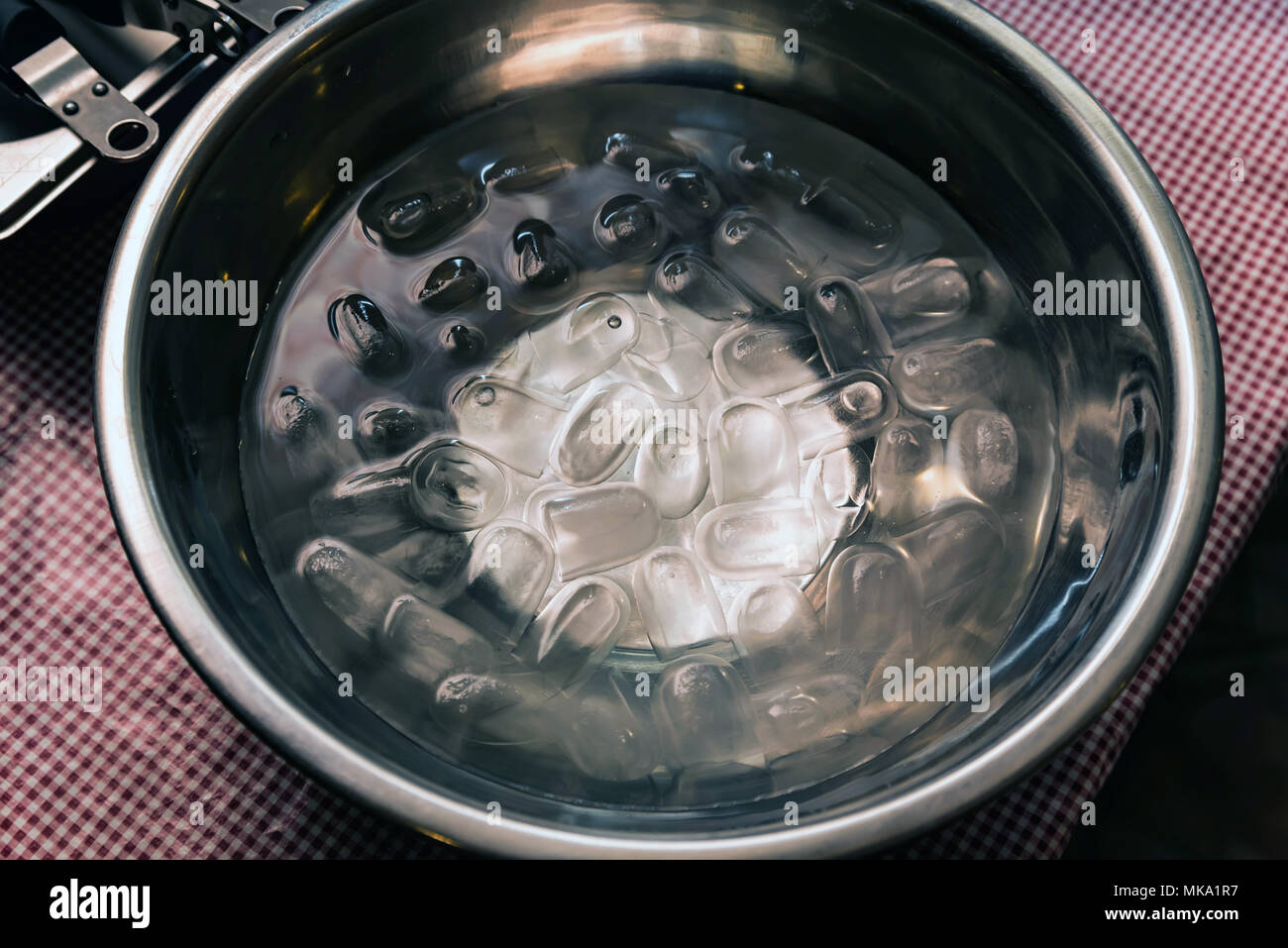 Ice cubes melt in metal bucket Stock Photo - Alamy